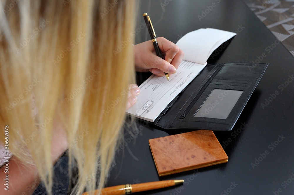 jeune femme remplissant un chèque,remplir un chèque, payer par chèque ...