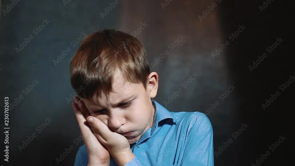little boy has a toothache studio on black background. Young blond ...