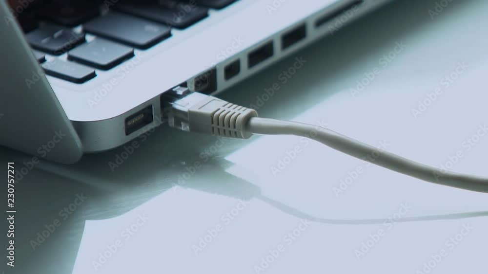 Female fingers plugging in ethernet cable into laptop port, network ...