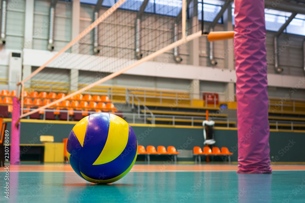 Yellow-blue volleyball on the floor in the gym, team of athletes ...