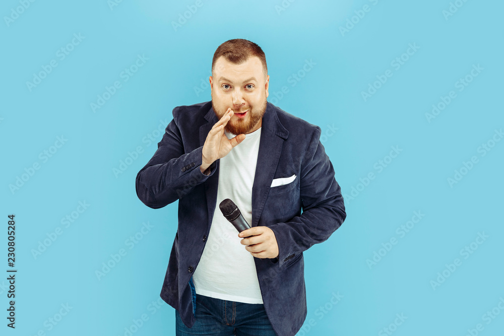 Young man with microphone on blue studio background, leading concept ...