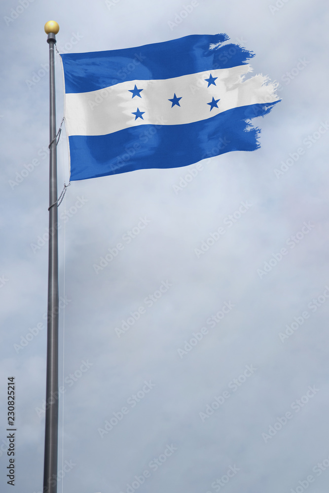Worn and tattered Honduras flag blowing in the wind on a cloudy day ...