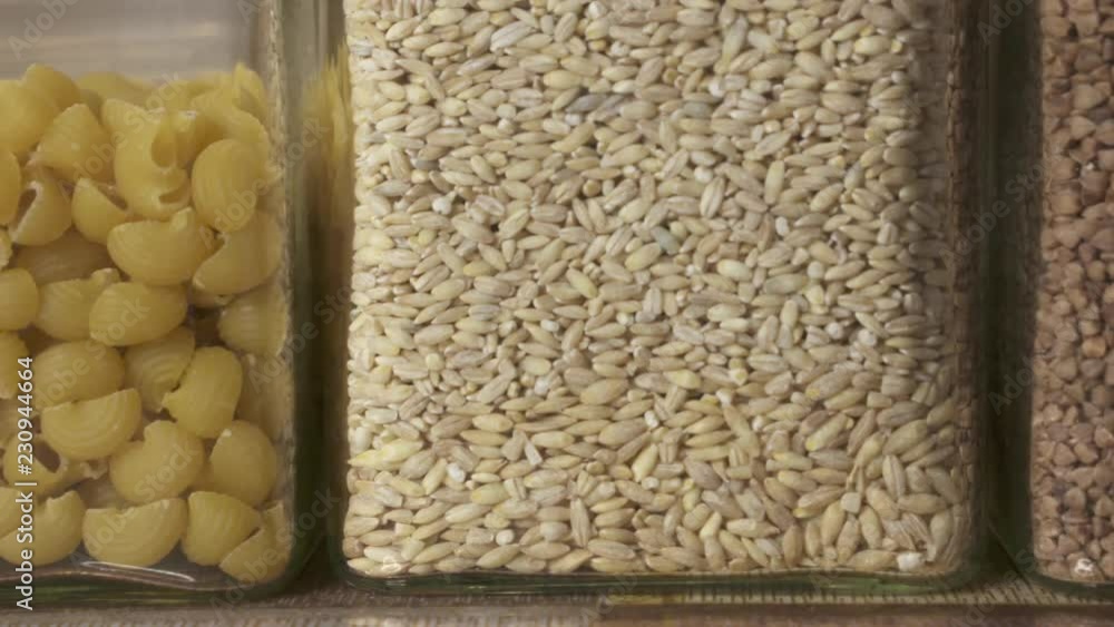 Variety of whole grains and pasta in kitchen glass cereal storage jars ...