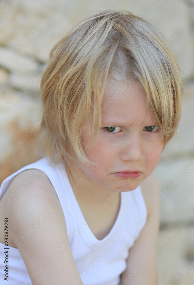 Un petit garçon blond boude pas content Photos | Adobe Stock