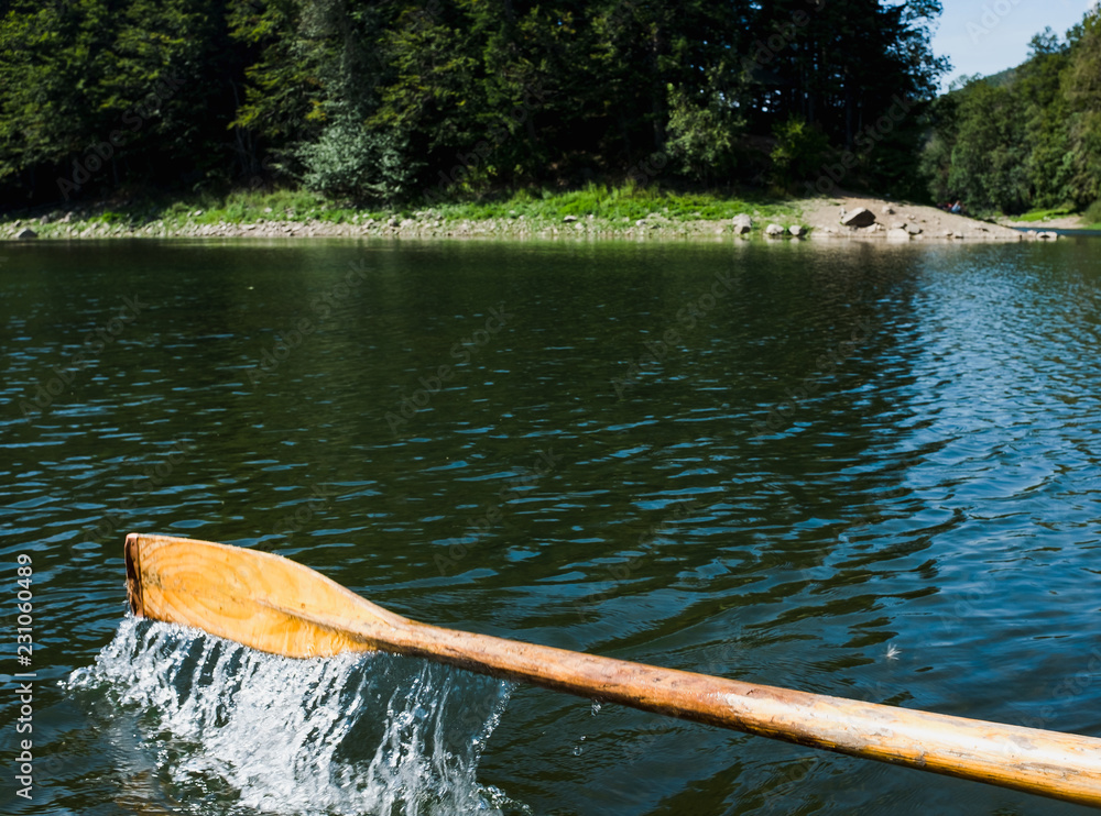Oar of boat touching water and causing splash and ripples in the water ...