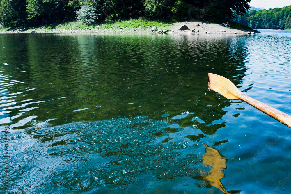 Oar of boat touching water and causing splash and ripples in the water ...