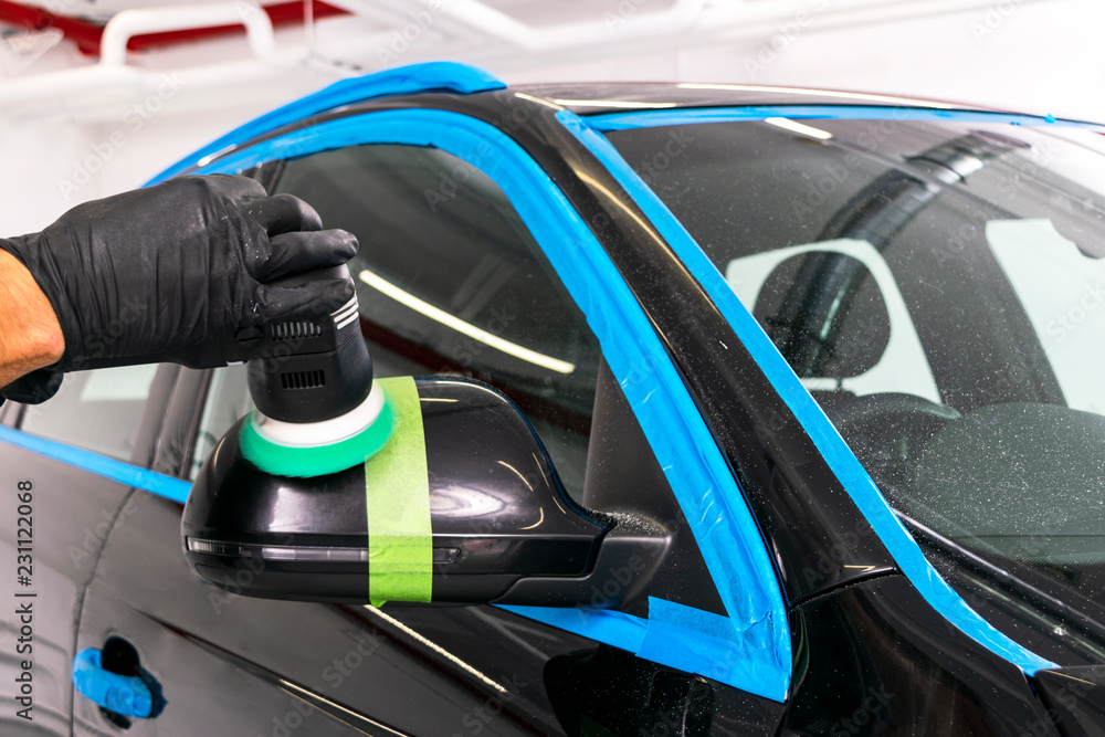 Car polish wax worker hands applying protective tape before polishing ...