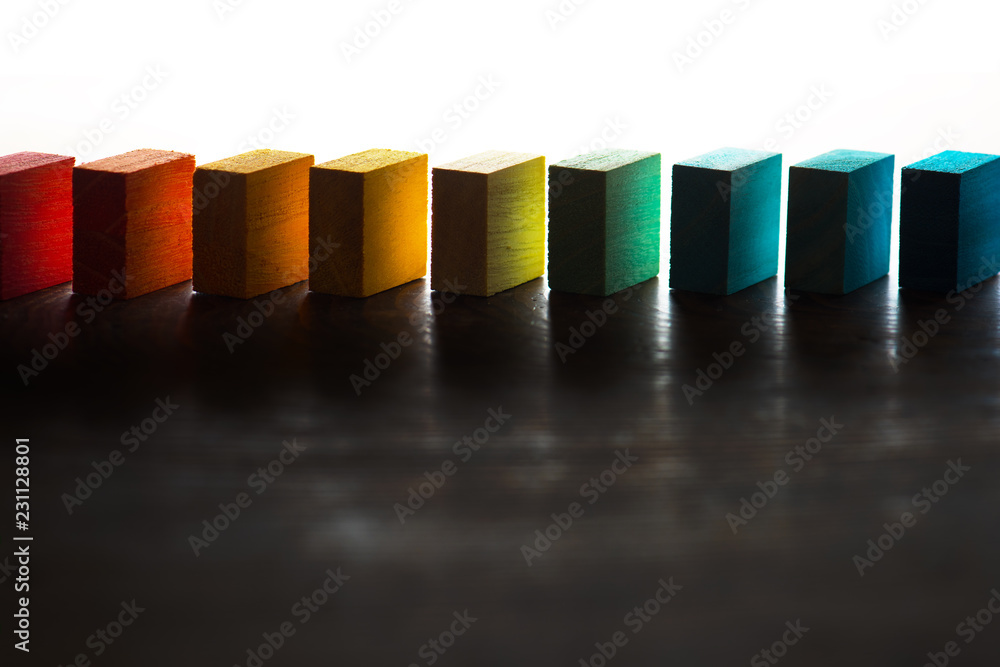 Colored wooden blocks diagonally aligned in light and shadow. On an ...