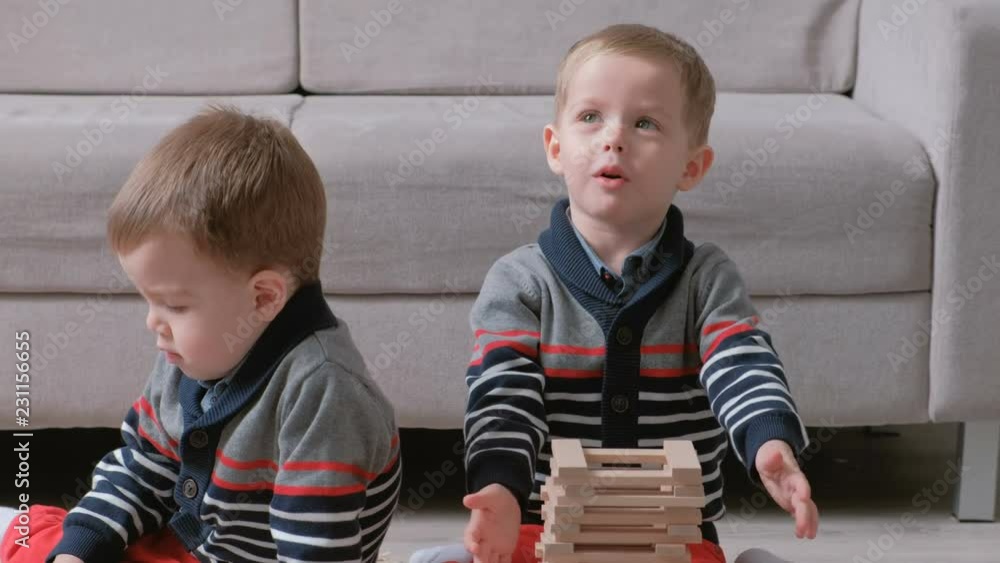 Twins boys brothers are building from wooden blocks sitting on the ...
