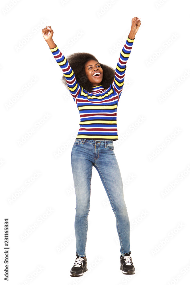 Full body cheerful young black woman cheering with arms raised against ...