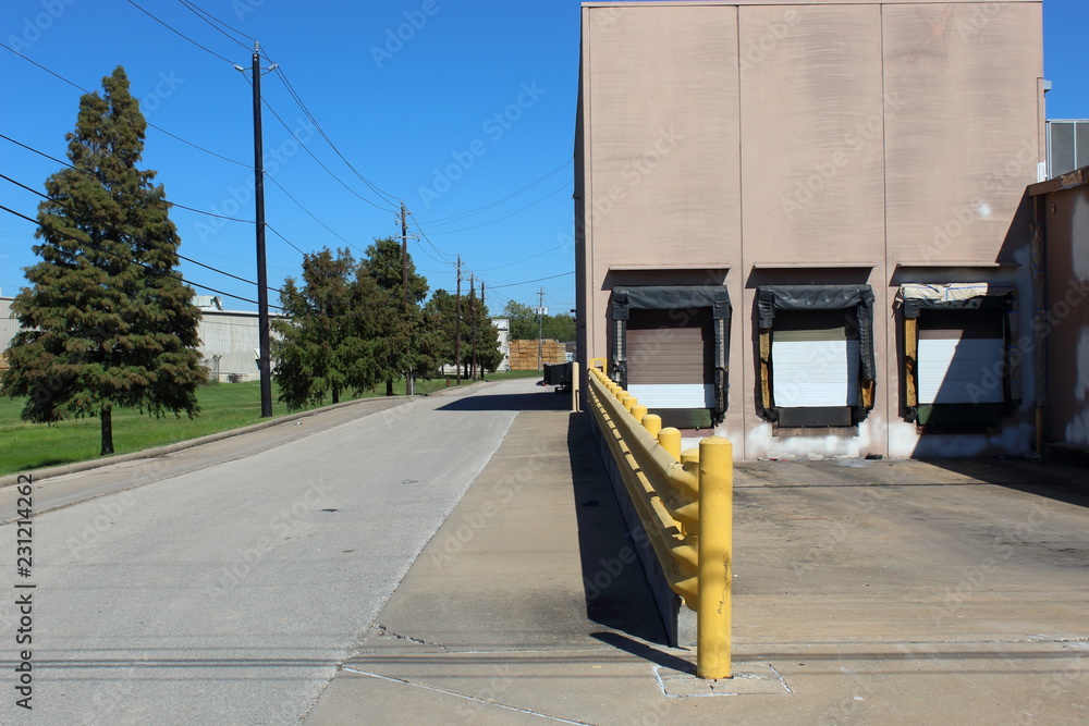 Loading dock behind a building with a yellow guard rail . The alley ...