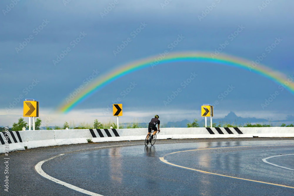 Beautiful rainbow in thailand. People are biking along the scenic road ...