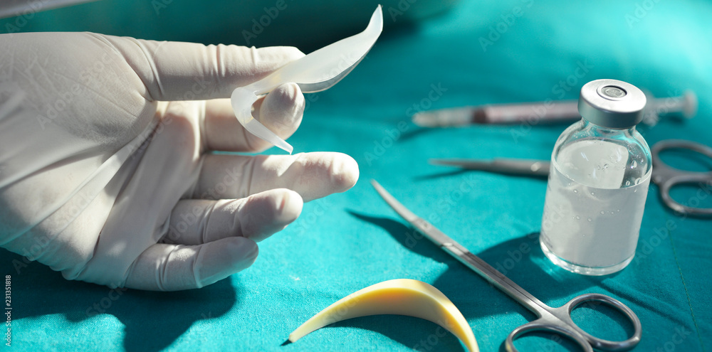Hand holding silicone nasal implant in operating room with surgical ...