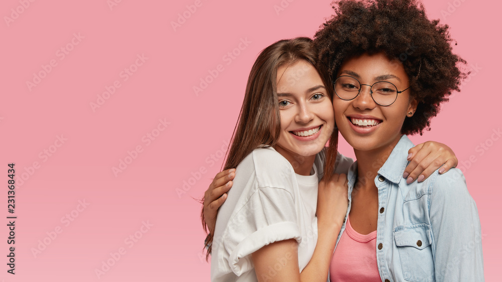 Multiracial cheerful young best friends embrace affectionately, have ...