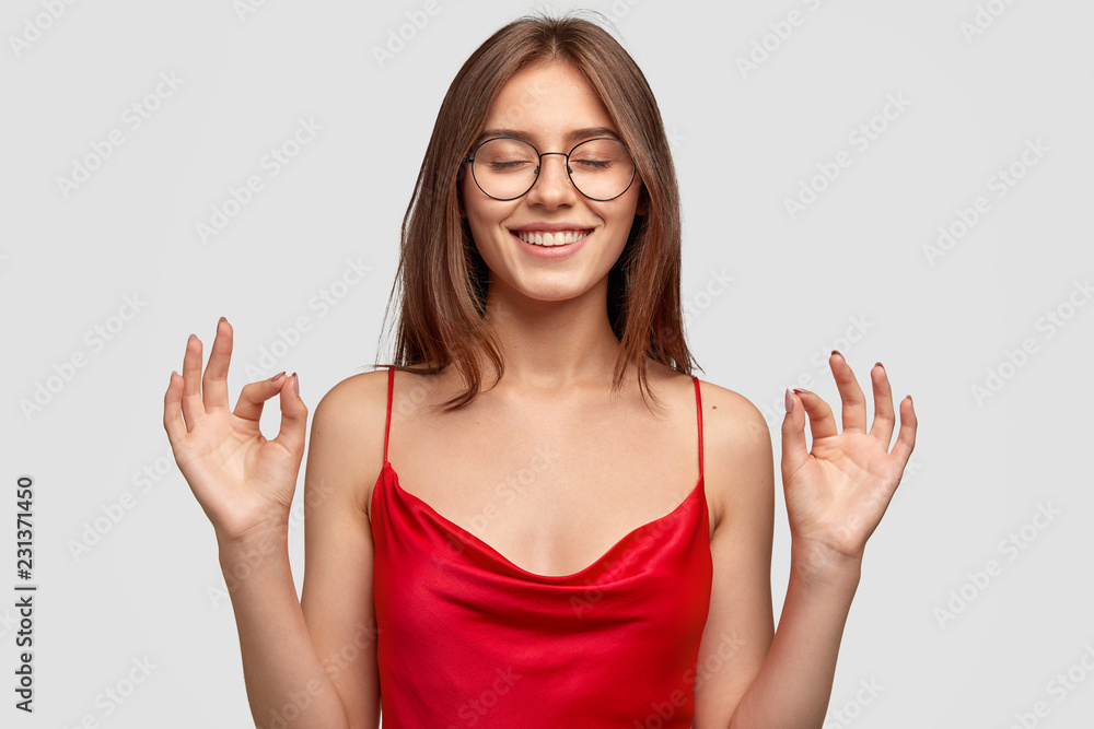 Relaxed calm female model with gentle smile, makes zero or okay gesture ...