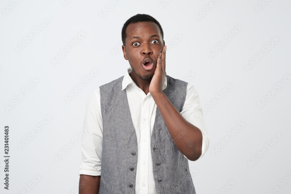 Puzzled or suprised african man dressed in white shirt and vest looking ...