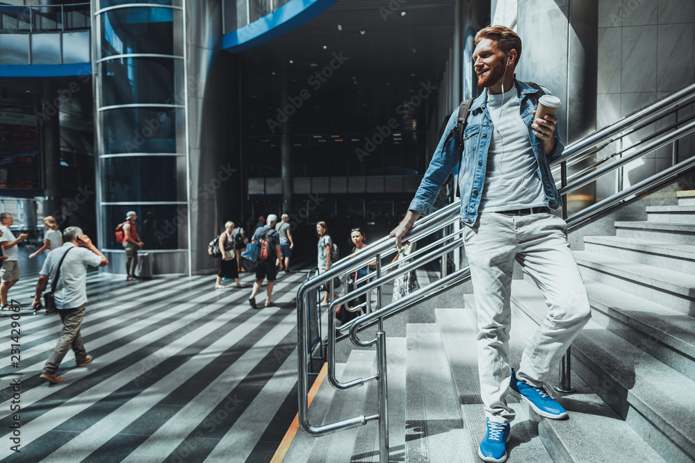 Full length of a positive adult man leaning on the handrail while ...