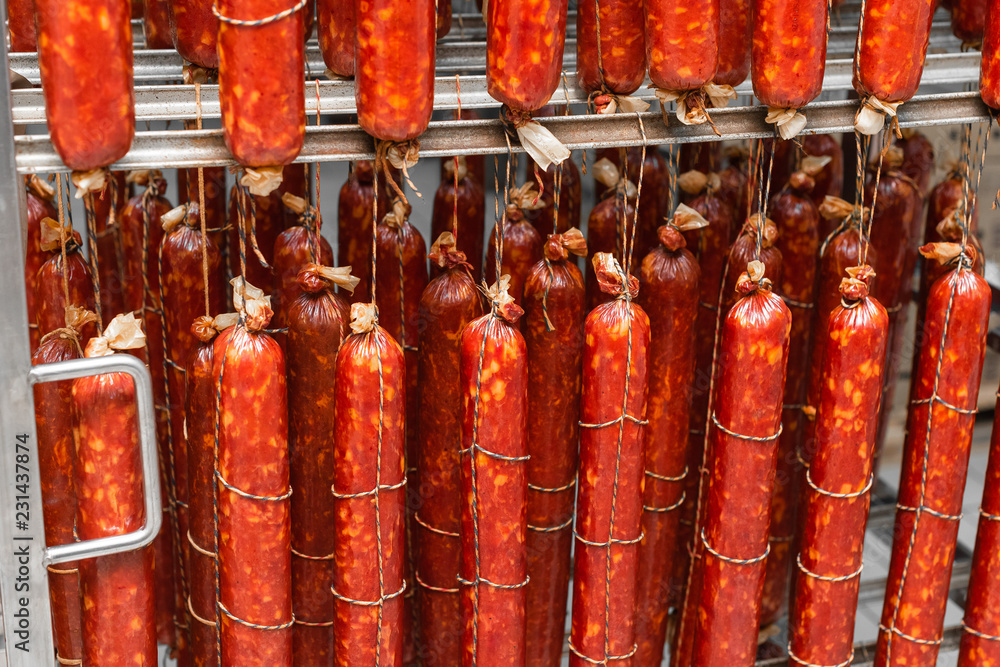 Smoked sausage suspended on a rope on a metal frame in the smokehouse ...
