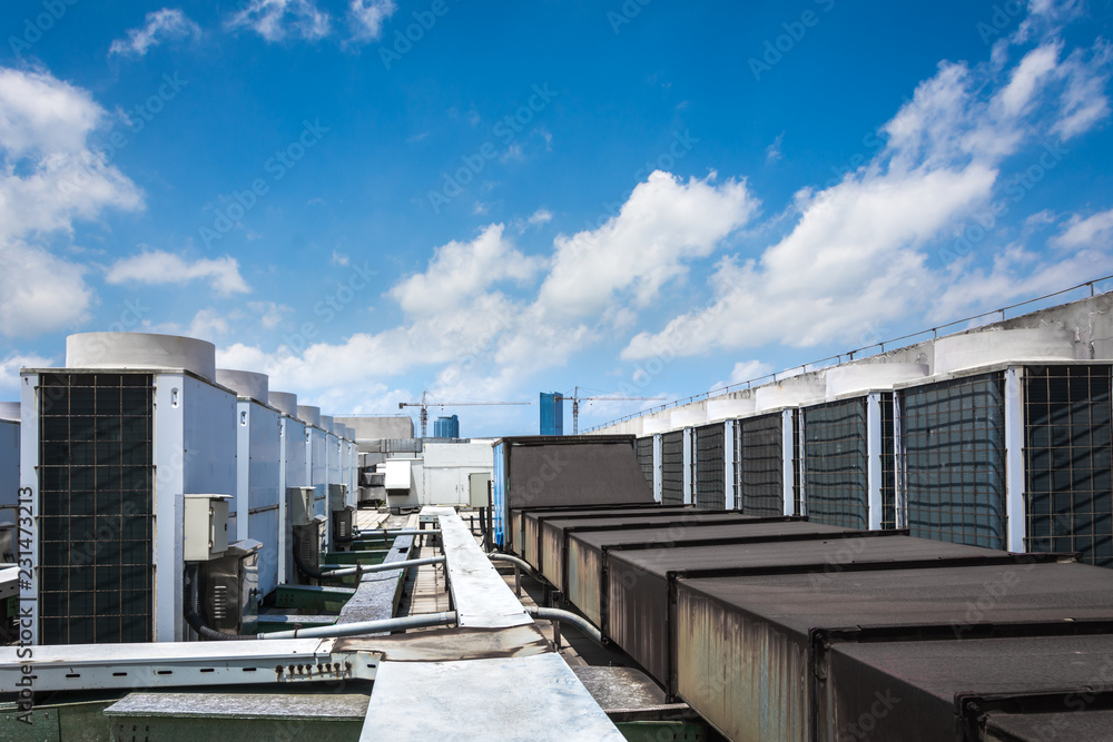 Square air-conditioning unit on the roof with a round fan. In the ...