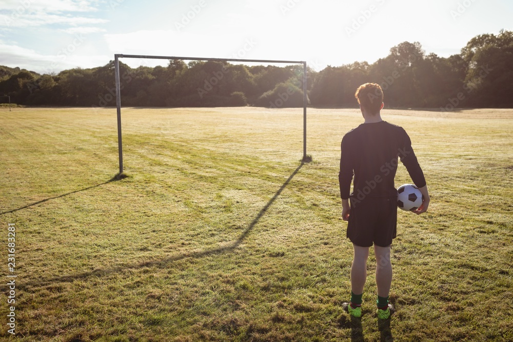 Football player standing with soccer ball in the field Stock Photo ...