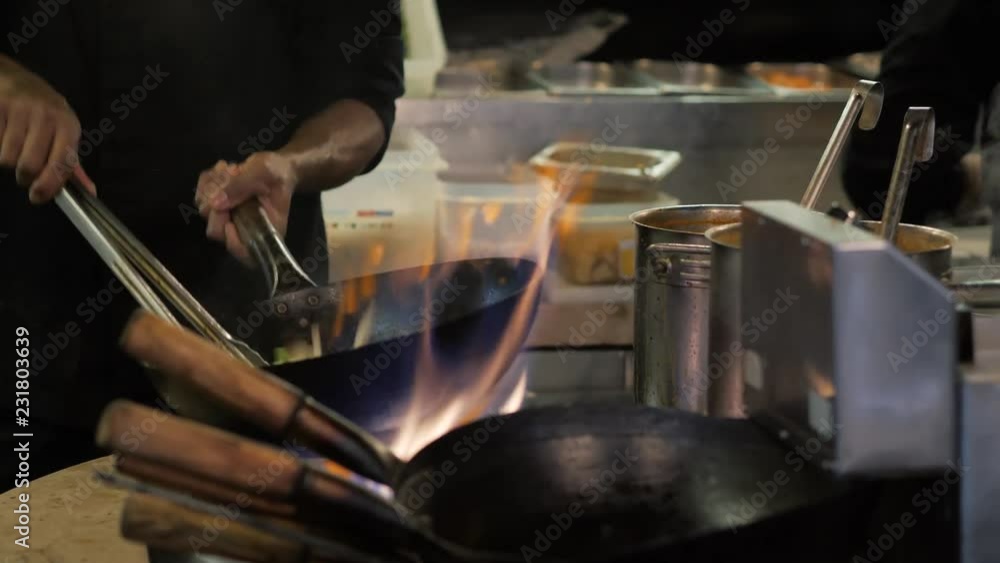 Chef is stirring vegetables in wok noodles fire flambe asia kitchen ...