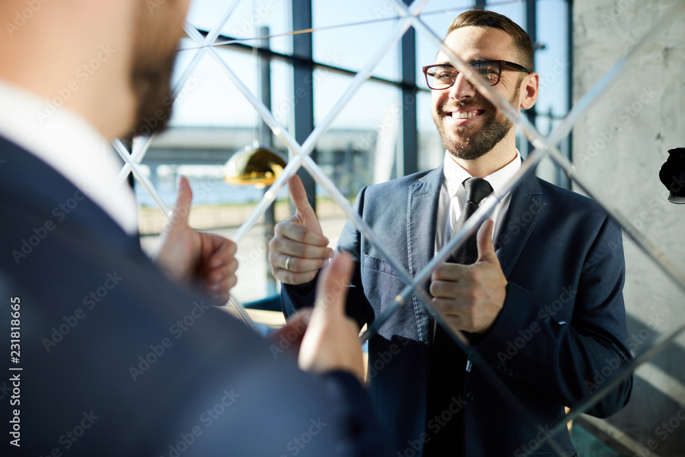 Successful businessman looking in mirror and showing thumbs up to ...
