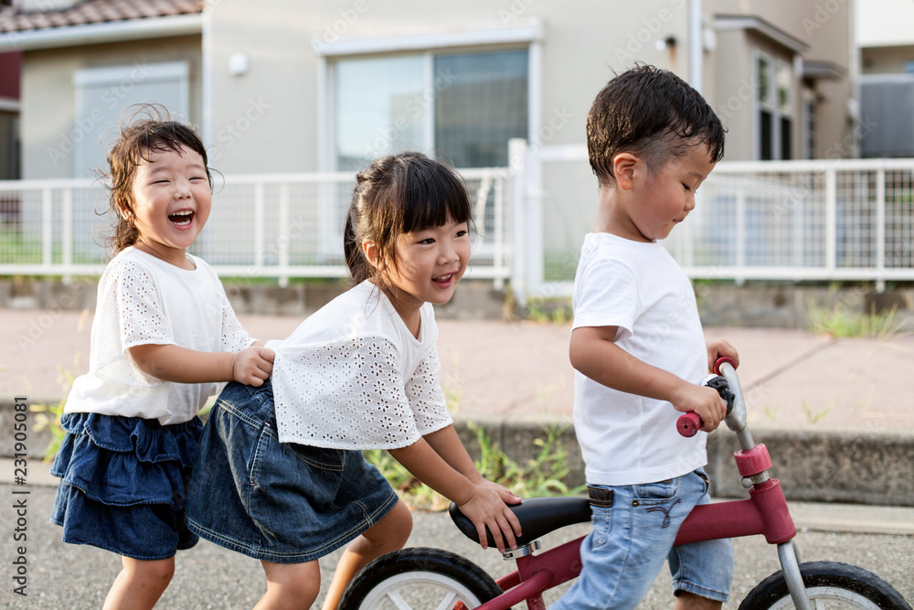 Smiling friends playing on street with bicycle Stock Photo | Adobe Stock