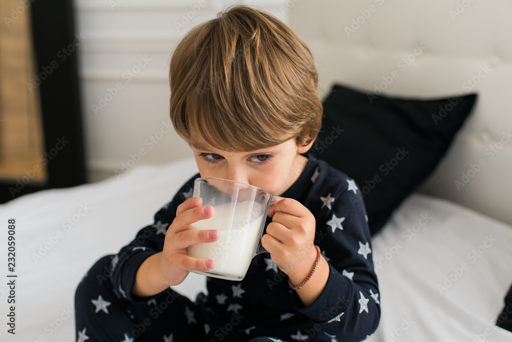 Beautiful happy kid drinking milk in the morning while sitting on the ...