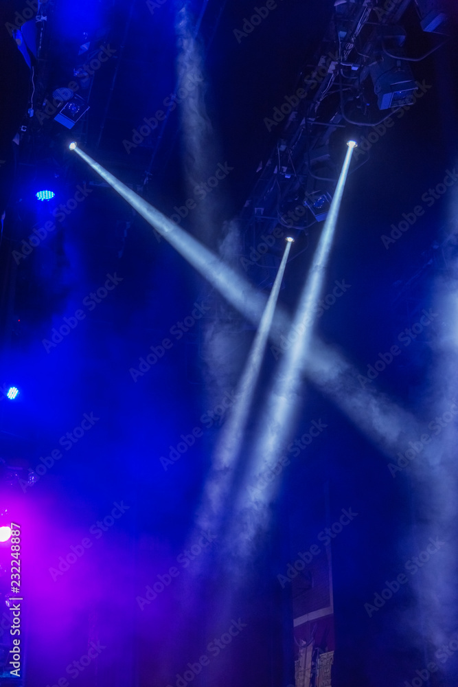 Stage lights. Several projectors in the dark. Multi-colored light beams ...
