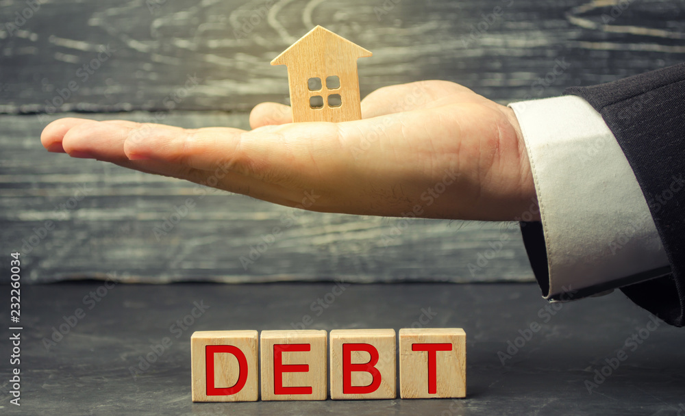 Miniature wooden house and the inscription " Debt ". Real estate, home ...