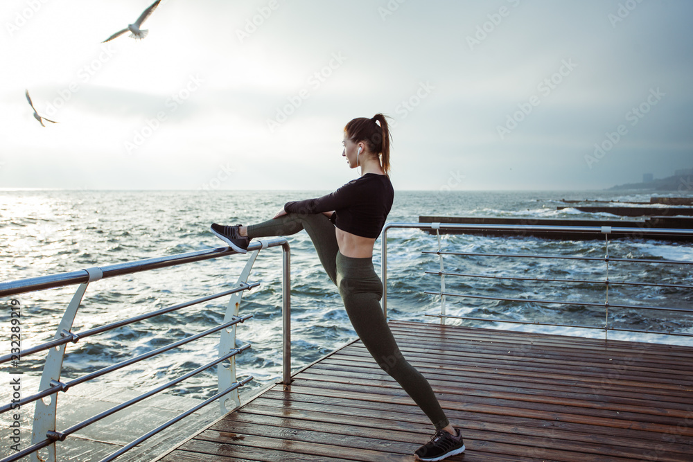 Fitness model athlete girl warm up stretching her hamstrings, leg and ...