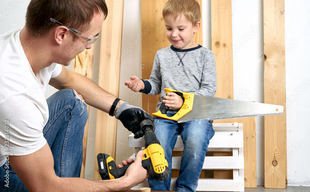 Fotka „Family time: Dad shows his son hand tools, a yellow screwdriver ...