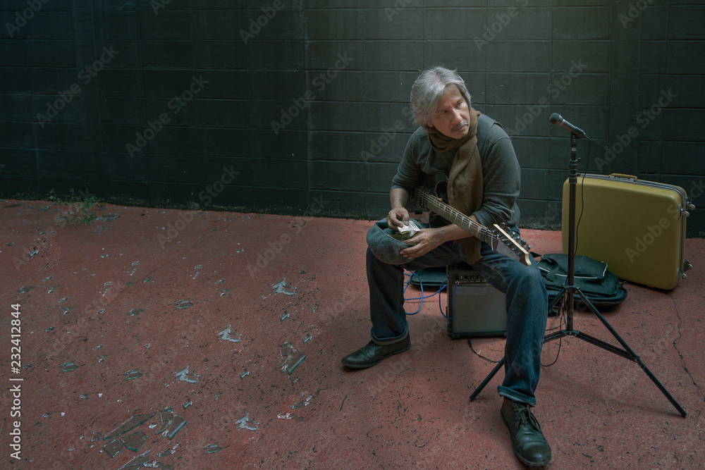 Asian attractive older homeless street musician relaxes his body on ...