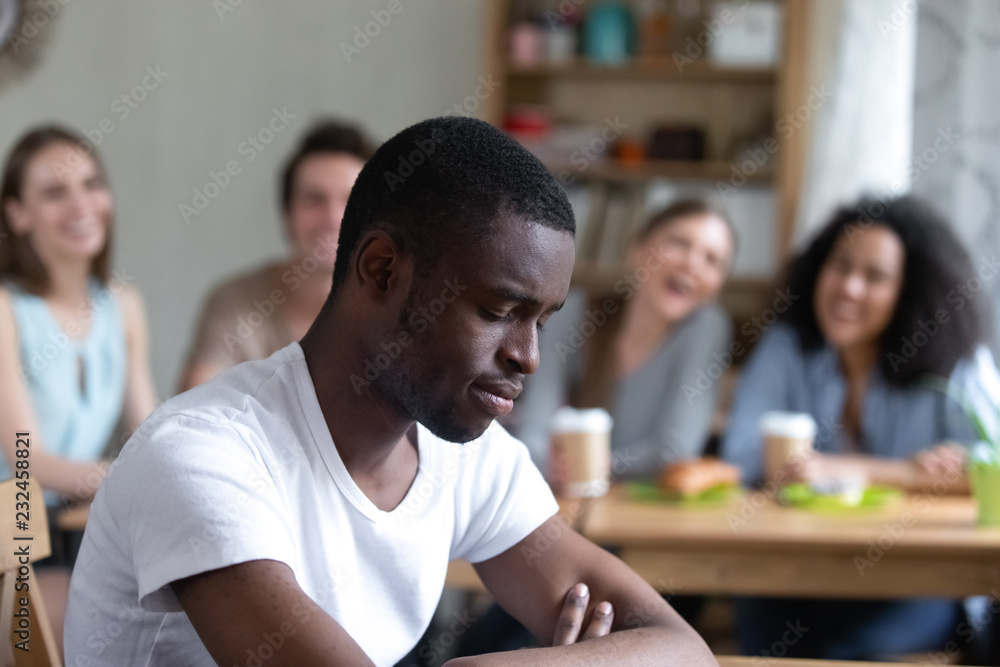 Group diverse people sitting in cafe laughing scoffing at black guy ...