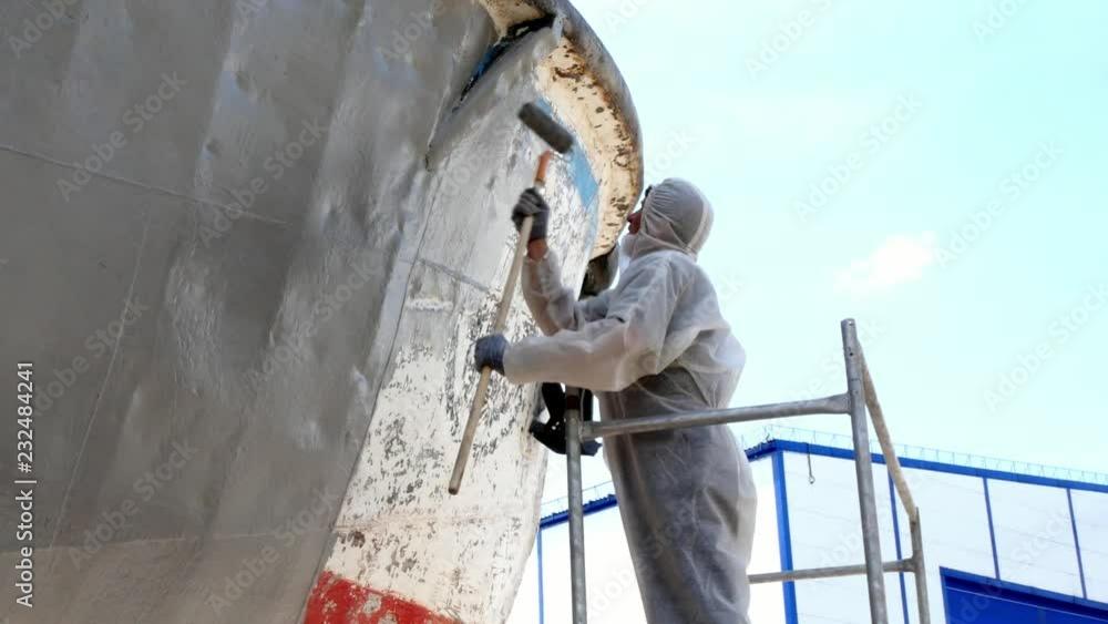 Vidéo Stock Worker paints metal of old rusty ship propeller at shipyard ...