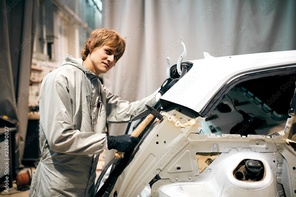 auto garage worker flatten metal body car with hammer in automotive ...