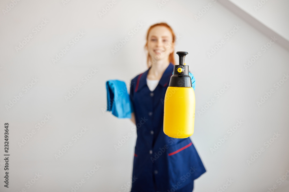 Happy hotel maid dressed in professional blue uniform holding wiper and ...