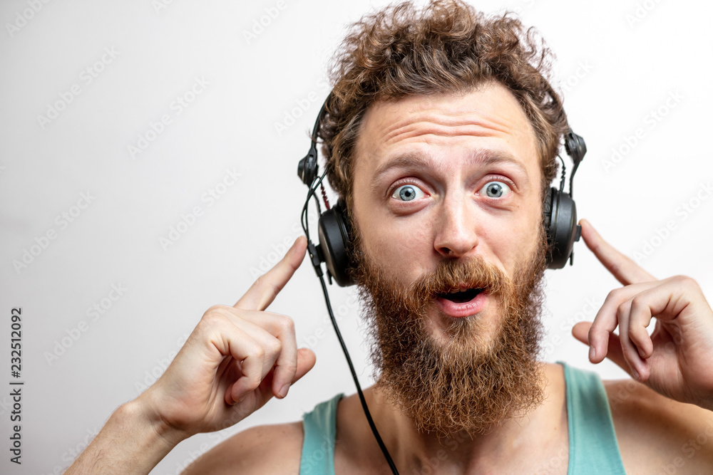 Handsome astonished male, wearing headphones, looking with great ...