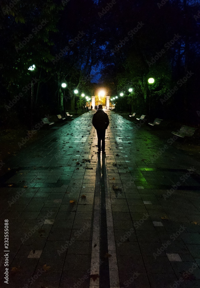 Man walking alone throug a dark street at night Stock-Foto | Adobe Stock