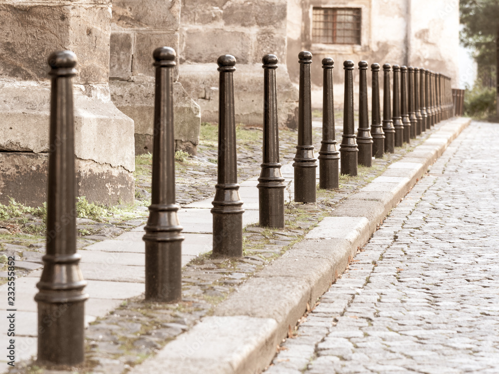 Row of iron pillars between cobbled street and pedestrian sidewalks ...