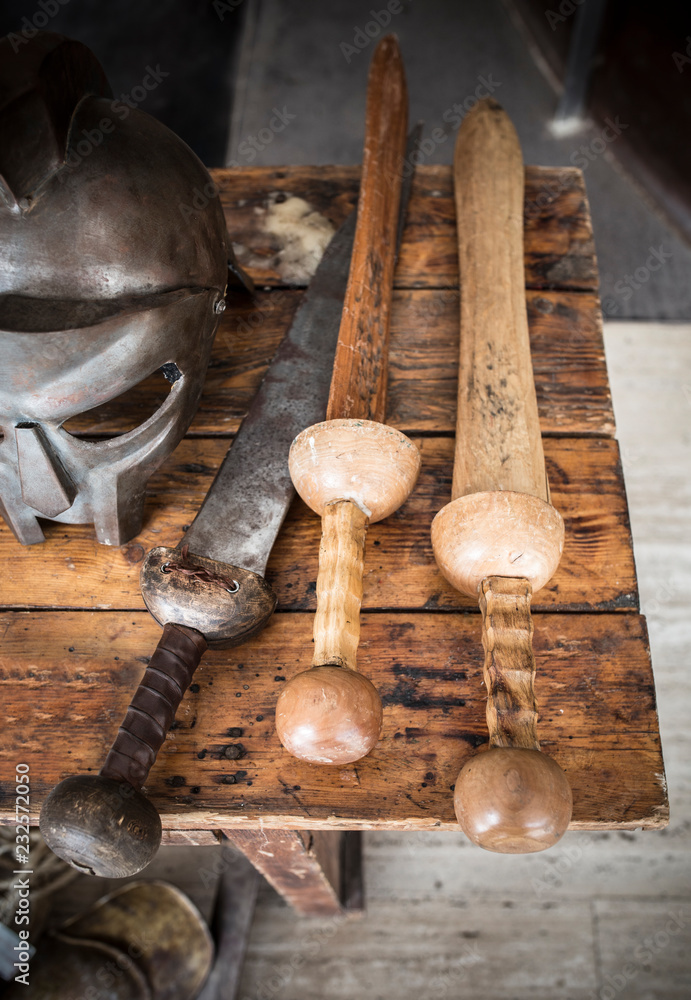 Gladiators table with helmet and training swords Stock Photo | Adobe Stock