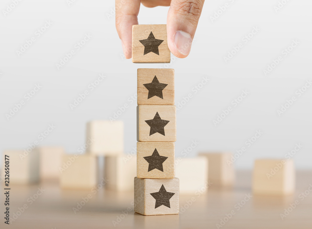 Hand arranging wooden blocks with the five star symbol. The best rating ...