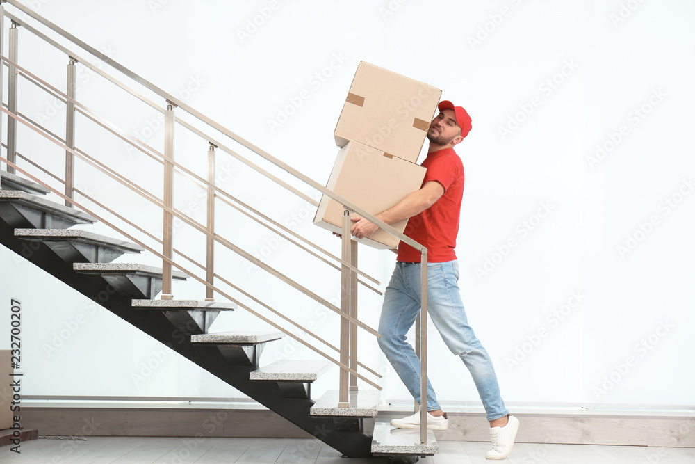 Man in uniform carrying carton boxes upstairs indoors. Posture concept ...