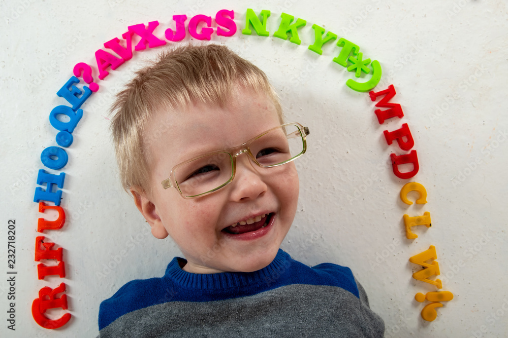 Happy charming Caucasian blond kid in colored clothes playing with ...