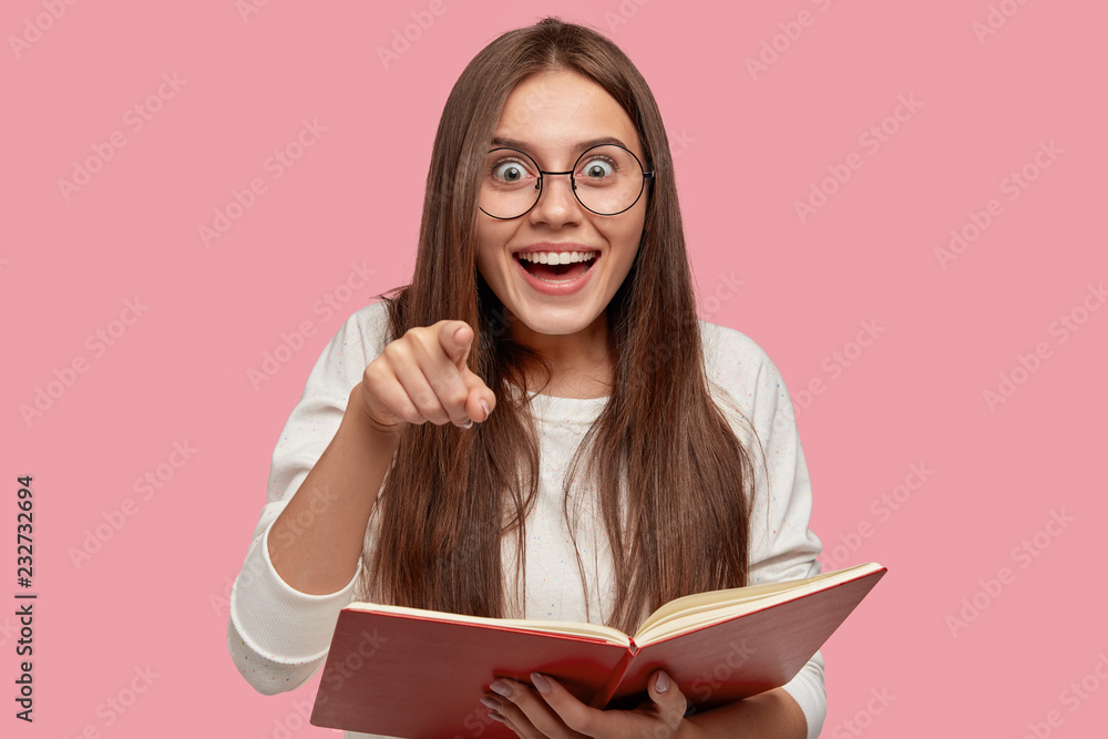 Lovely Glad Surprised Girl Smiles Broadly And Points Directly Into