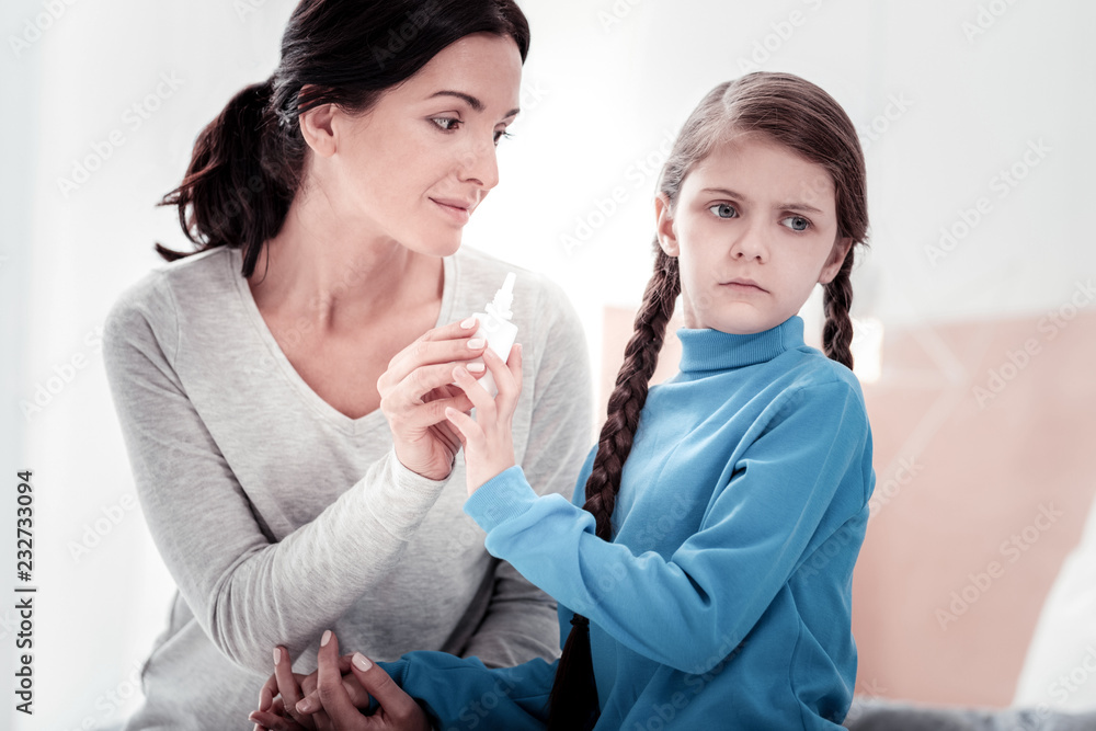 Disease. Portrait of young careful mother holding nasal drops while her ...