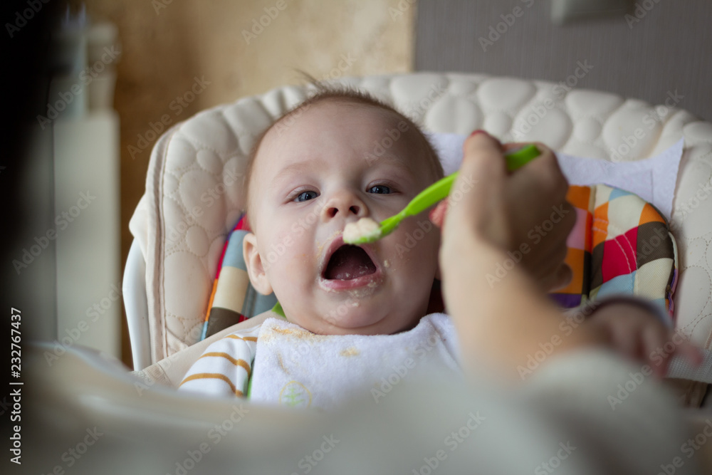 The first feeding of the baby from the spoon. Mom feeds baby ...