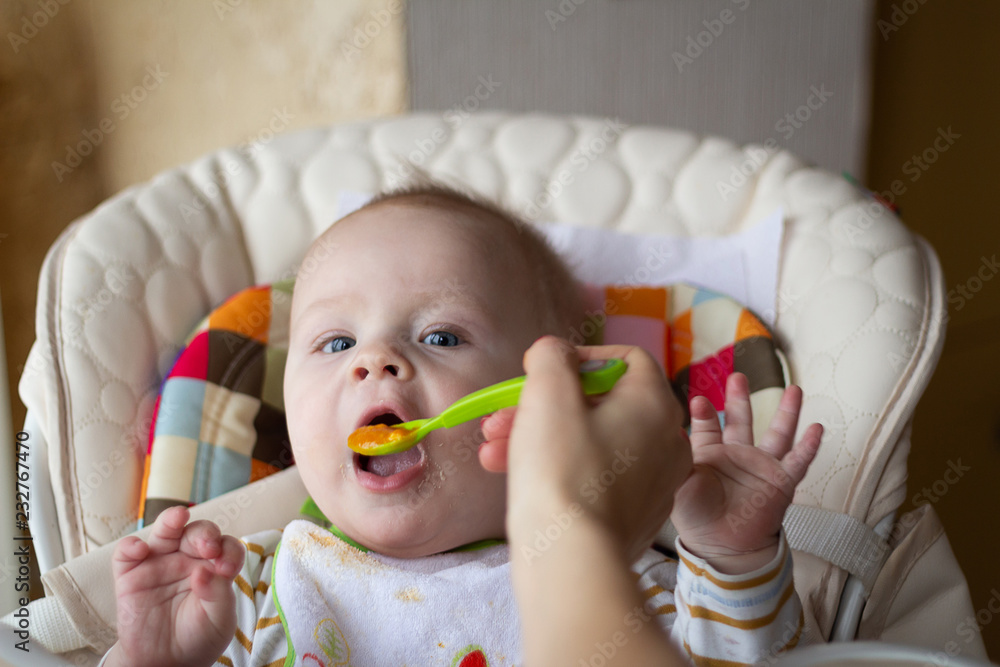 The first feeding of the baby from the spoon. Mom feeds baby ...