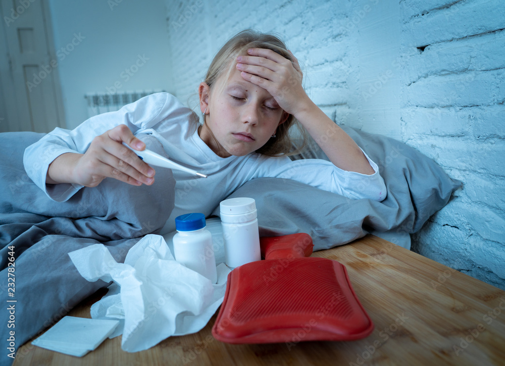 Little girl lying sick in bed feeling sick with high fever and headache ...