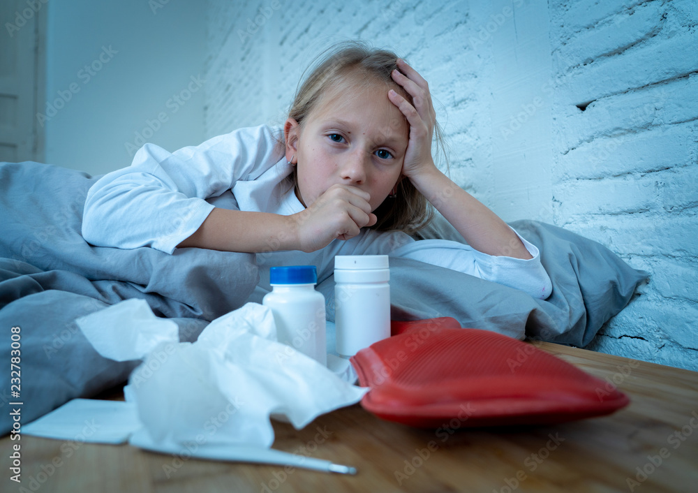 Little girl lying sick in bed coughing feeling sick with high fever ...